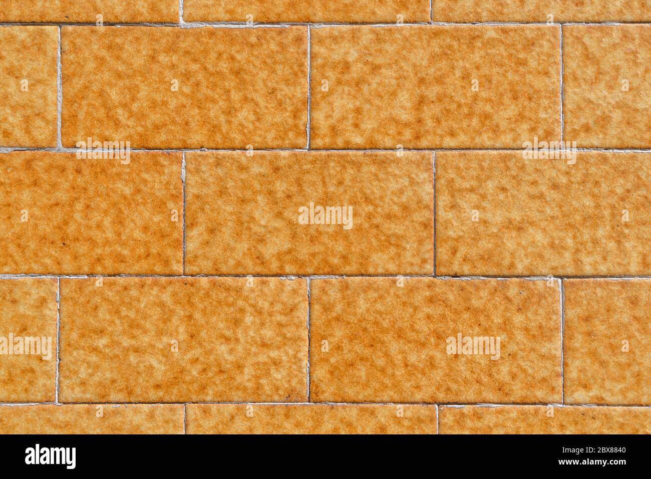 Yellow brick wall made of symmetrical stone blocks with orange and ...