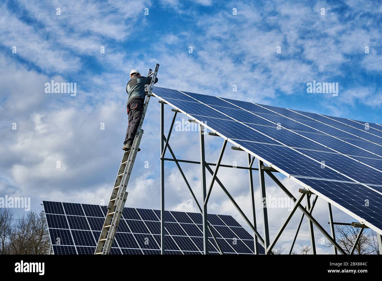 Man worker electrician repairing photovoltaic solar module, standing on ...