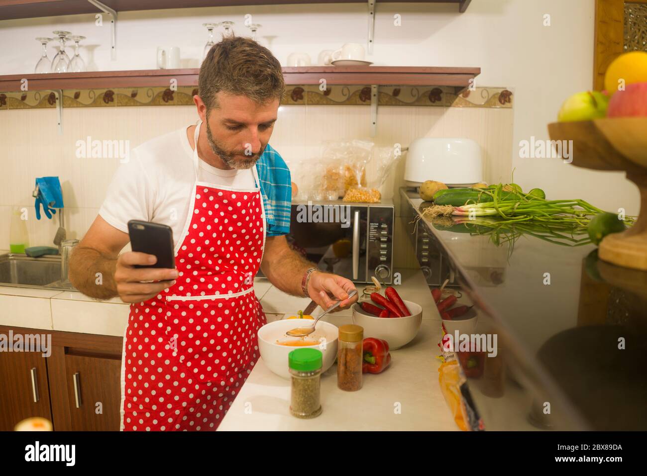 home lifestyle portrait of young happy and attractive home cook man in ...