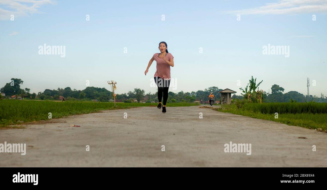 outdoors jogging - young happy and dedicated Asian Korean woman running ...