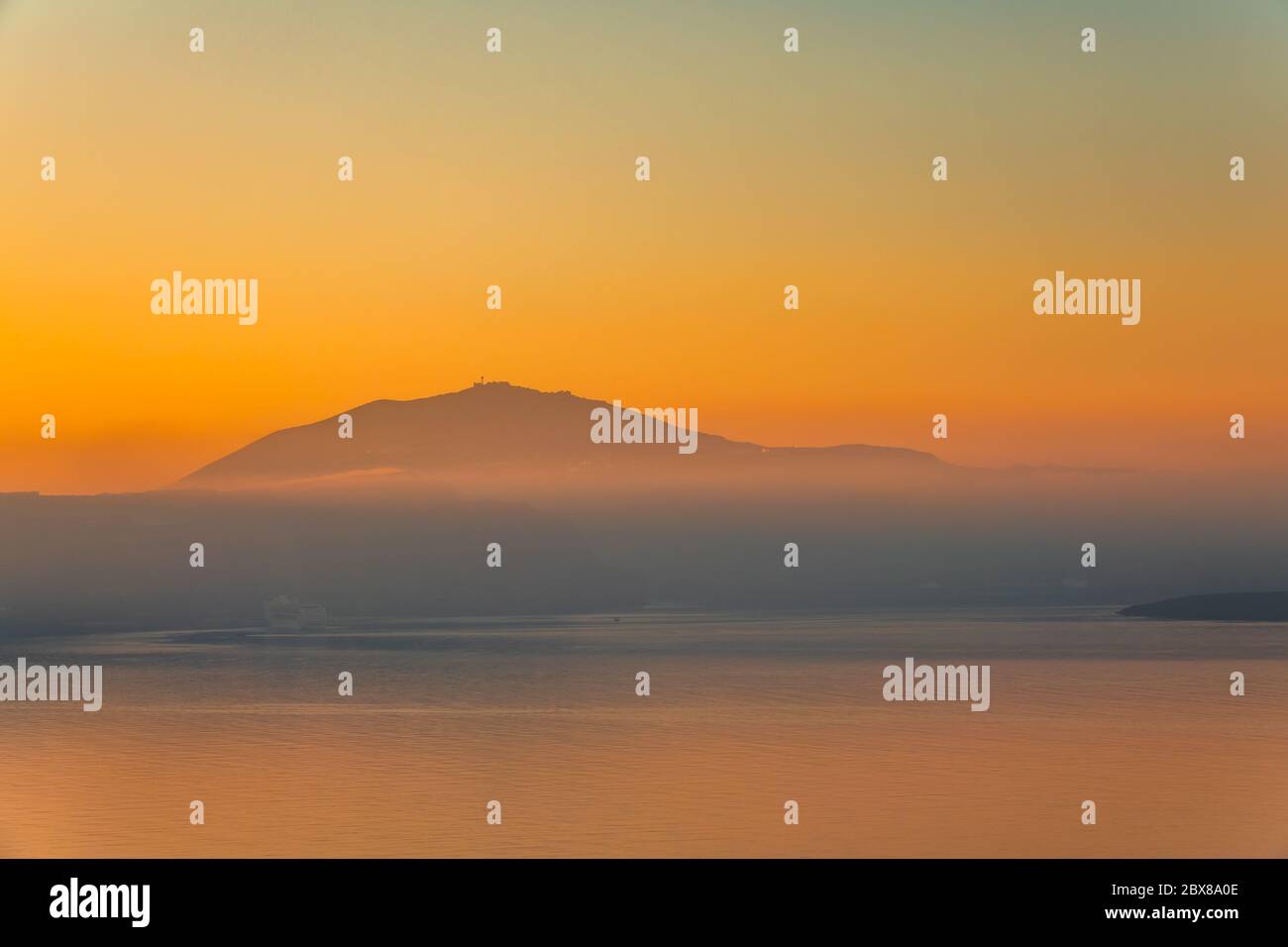 The calm surface of the sea after sunset. Orange sky and fog over the ...