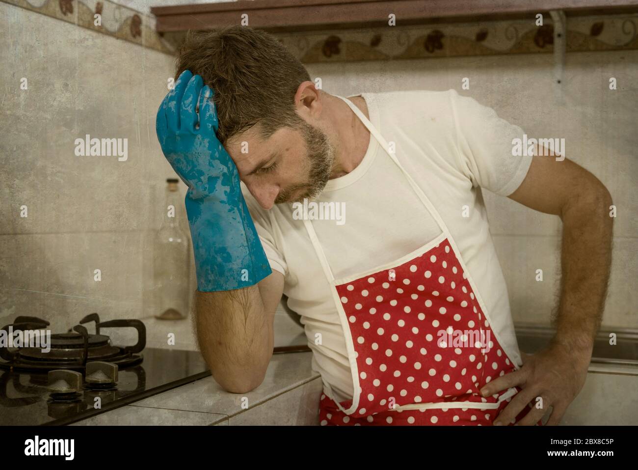 young attractive overworked and stressed home cook man in red apron ...