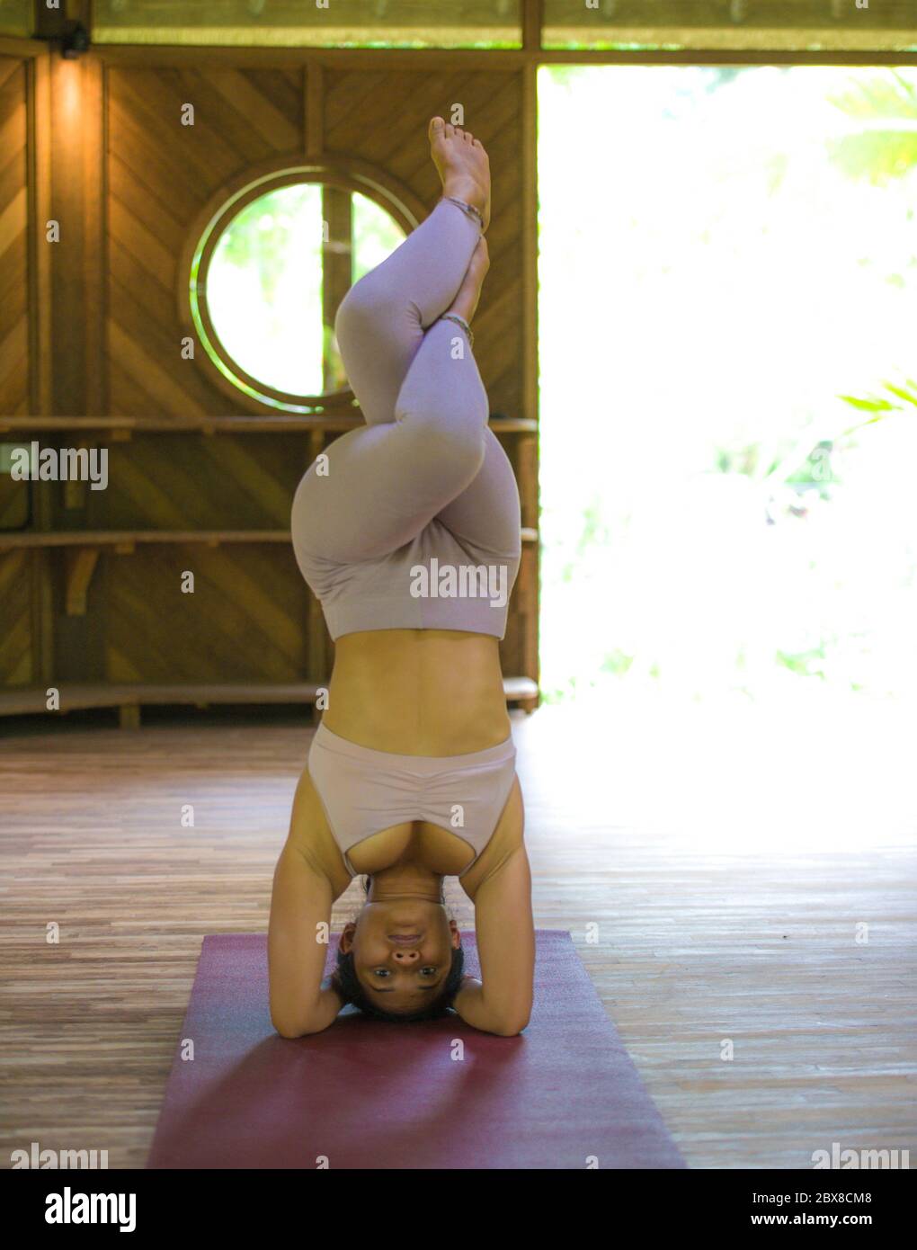 young attractive and healthy Asian Indonesian acrobat woman practicing acro yoga exercise in ...