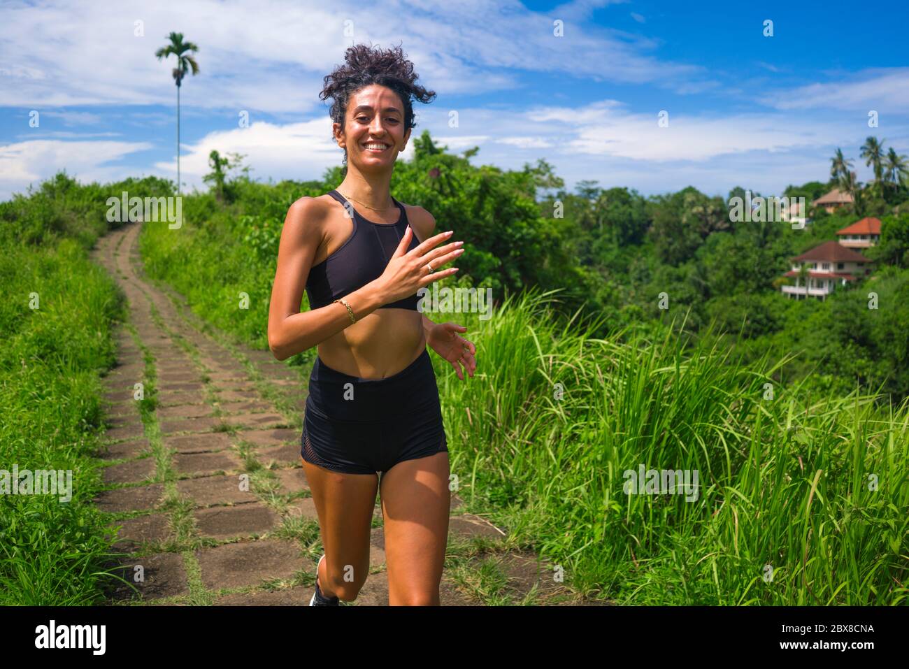 happy female runner training on countryside road - young attractive and ...