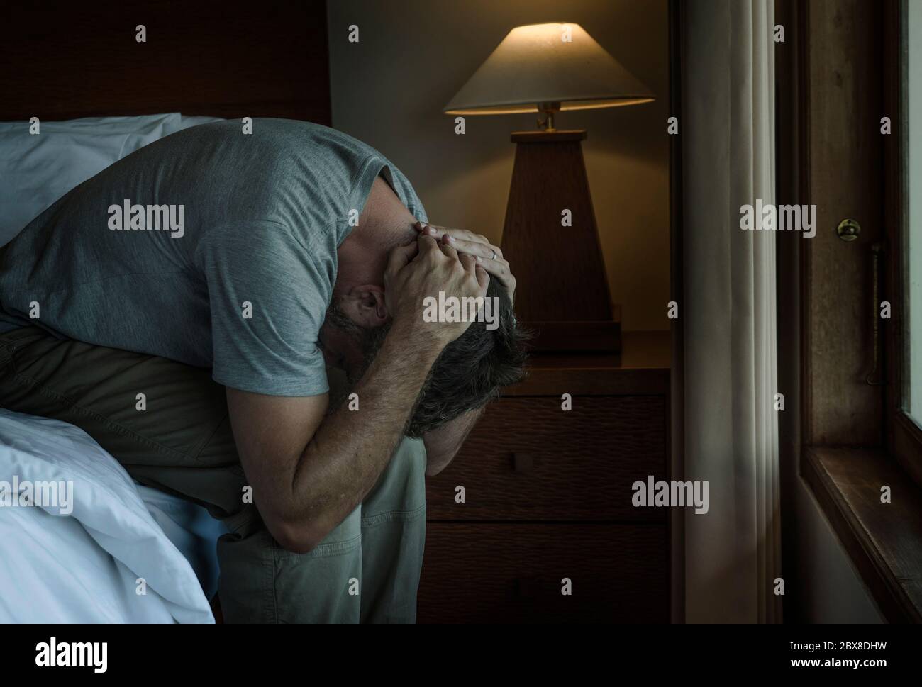 Attractive depressed and upset man at home bedroom . dramatic lifestyle ...