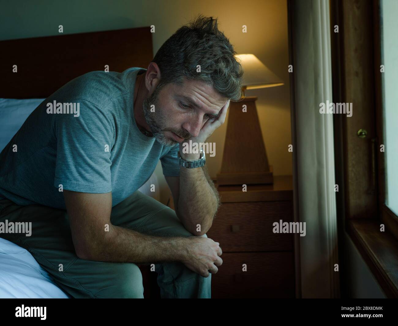 Attractive depressed and upset man at home bedroom . dramatic lifestyle ...