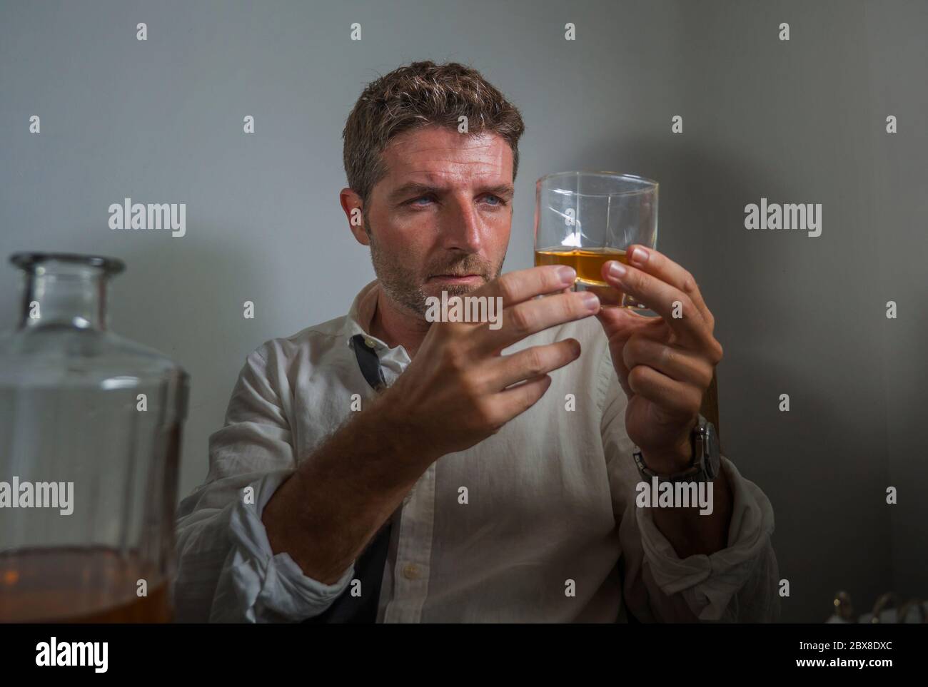 dramatic portrait of 30s to 40s alcoholic man in lose necktie drinking ...