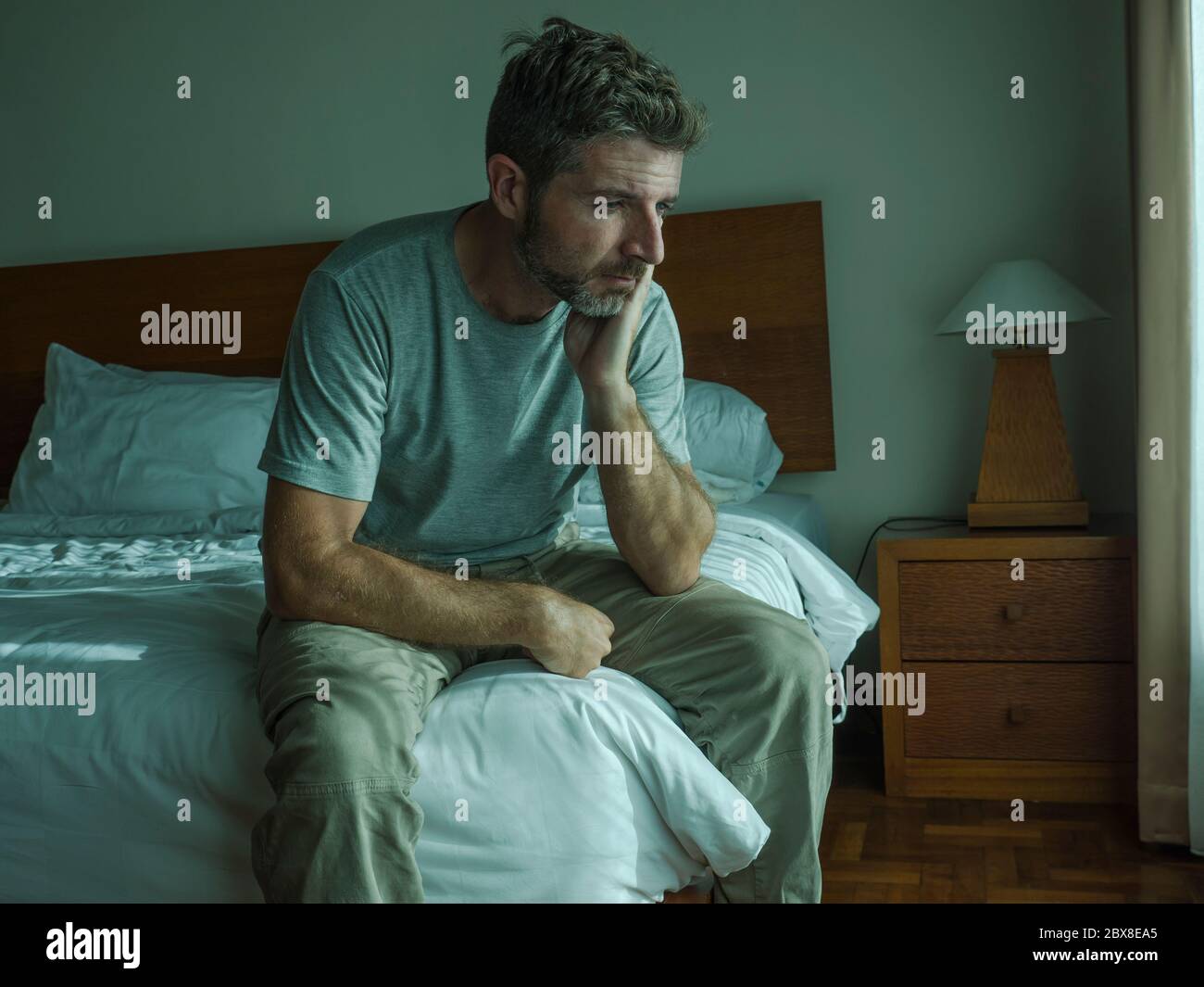 Attractive depressed and upset man at home bedroom . dramatic lifestyle ...