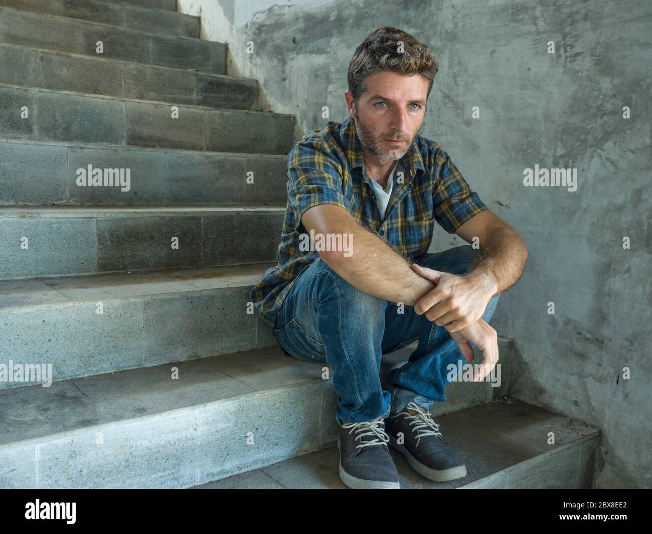 dramatic lifestyle portrait of young depressed and sad man sitting ...