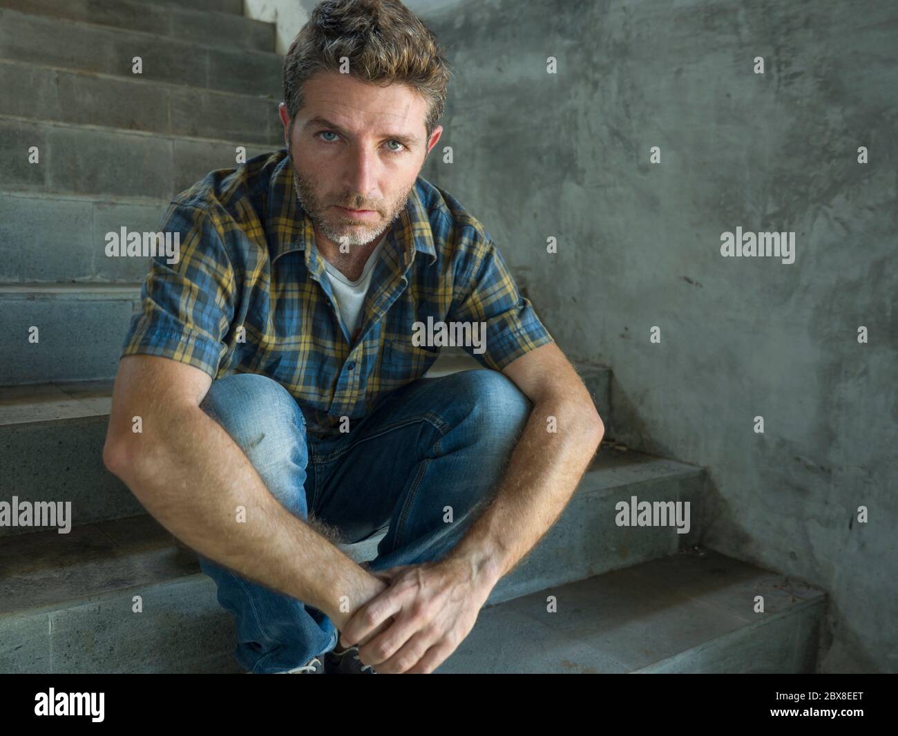 dramatic lifestyle portrait of young depressed and sad man sitting ...