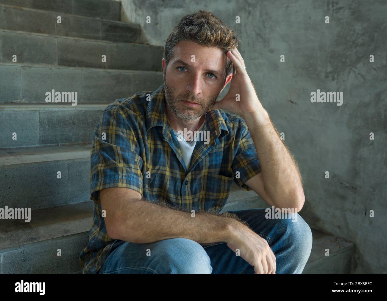 dramatic lifestyle portrait of young depressed and sad man sitting ...
