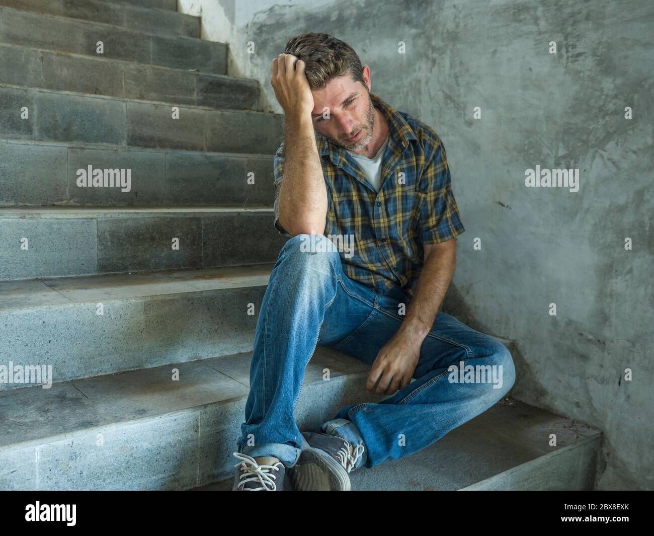 dramatic lifestyle portrait of young depressed and sad man sitting ...