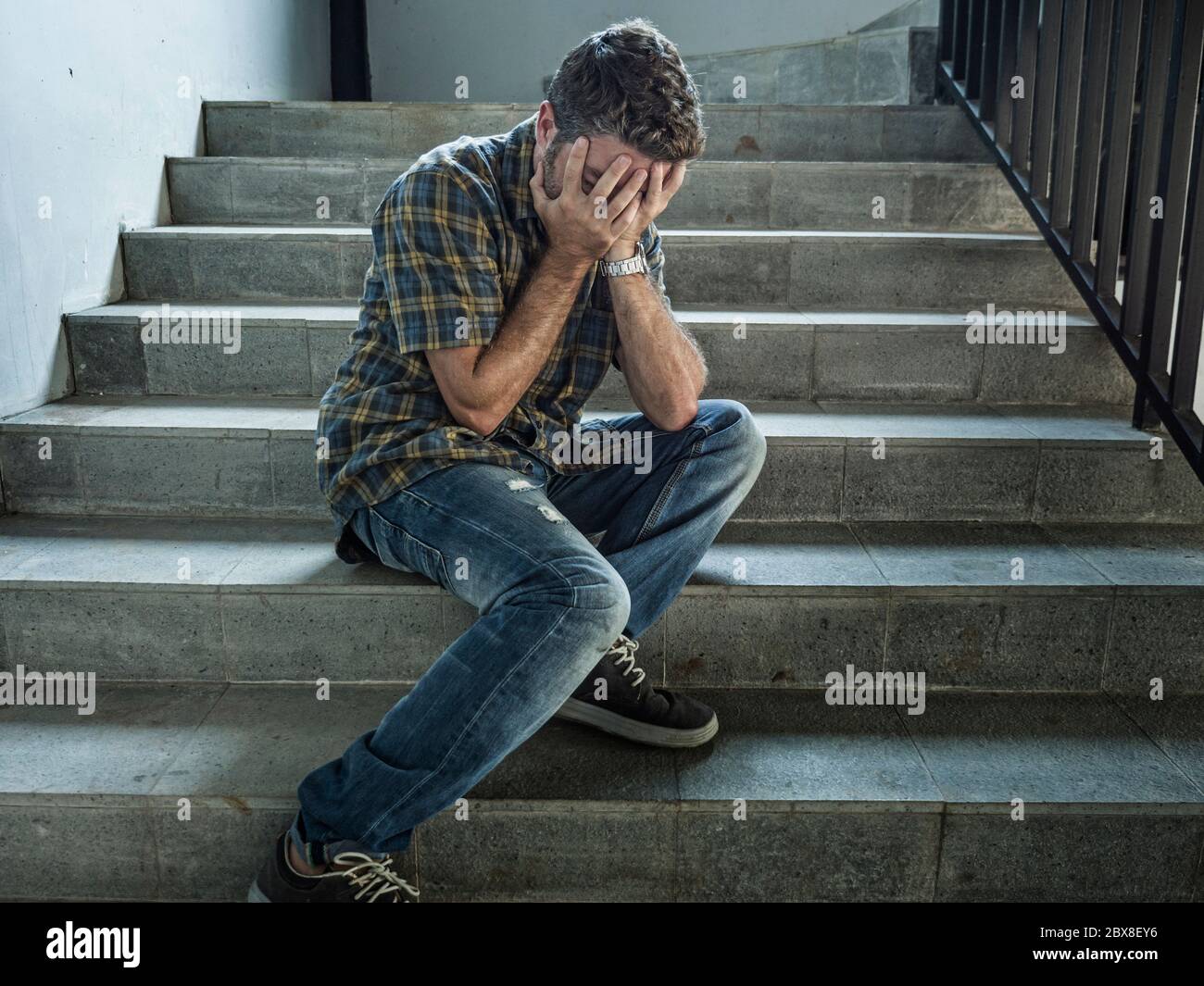 dramatic lifestyle portrait of young depressed and sad man sitting ...