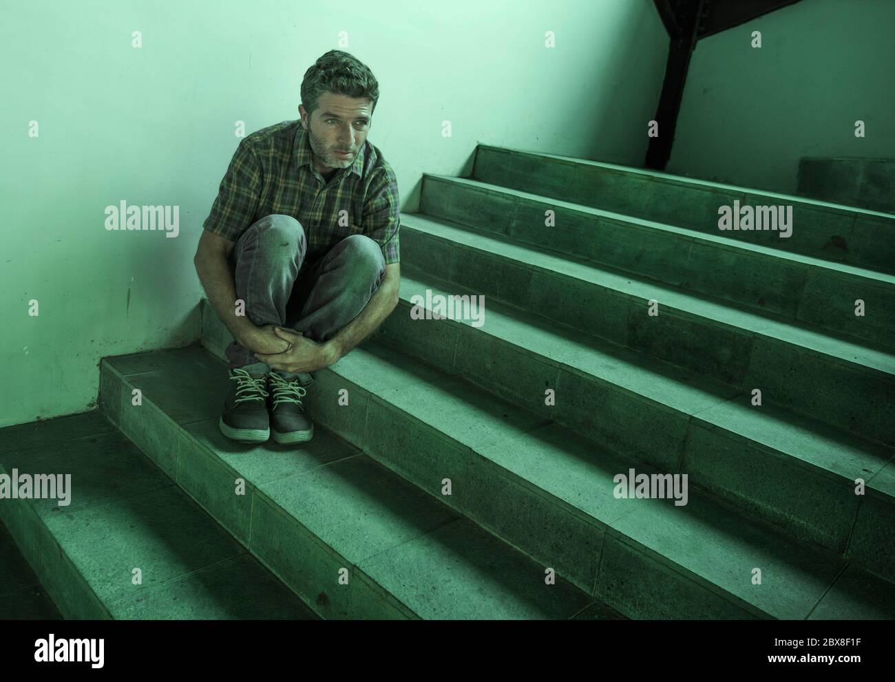 dramatic lifestyle portrait of young depressed and sad man sitting ...