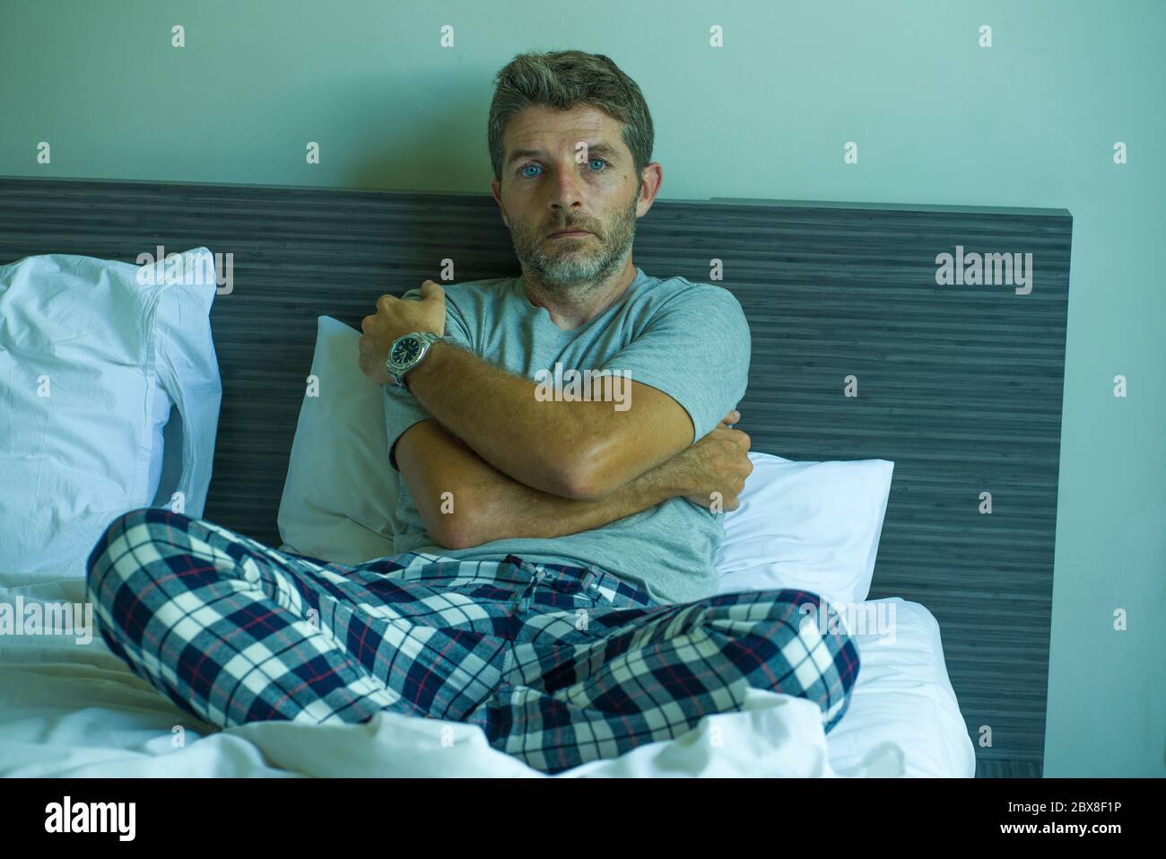 dramatic portrait of attractive scared and depressed 40s man on bed in ...