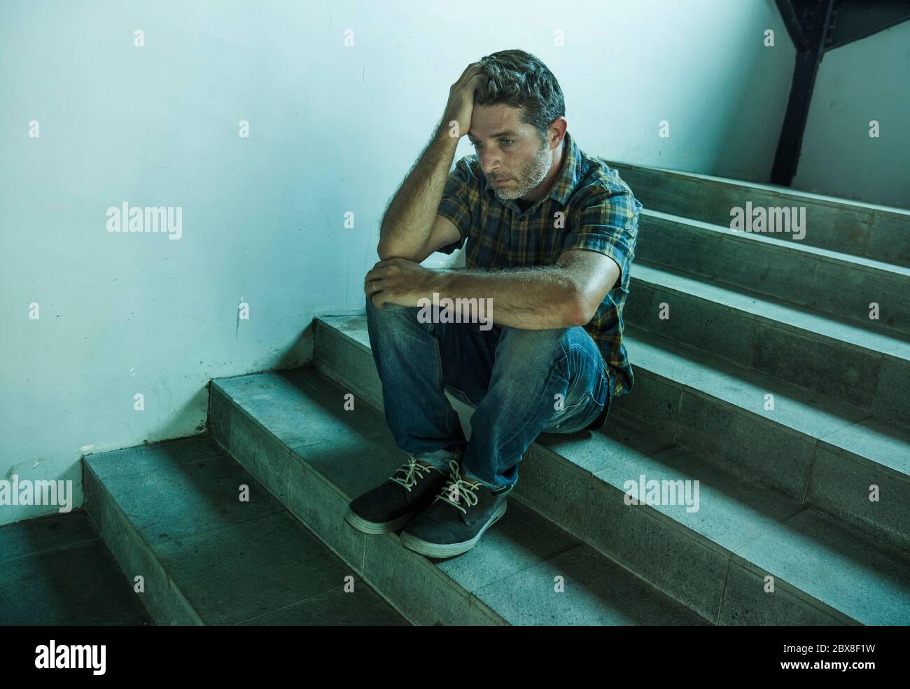 dramatic lifestyle portrait of young depressed and sad man sitting ...