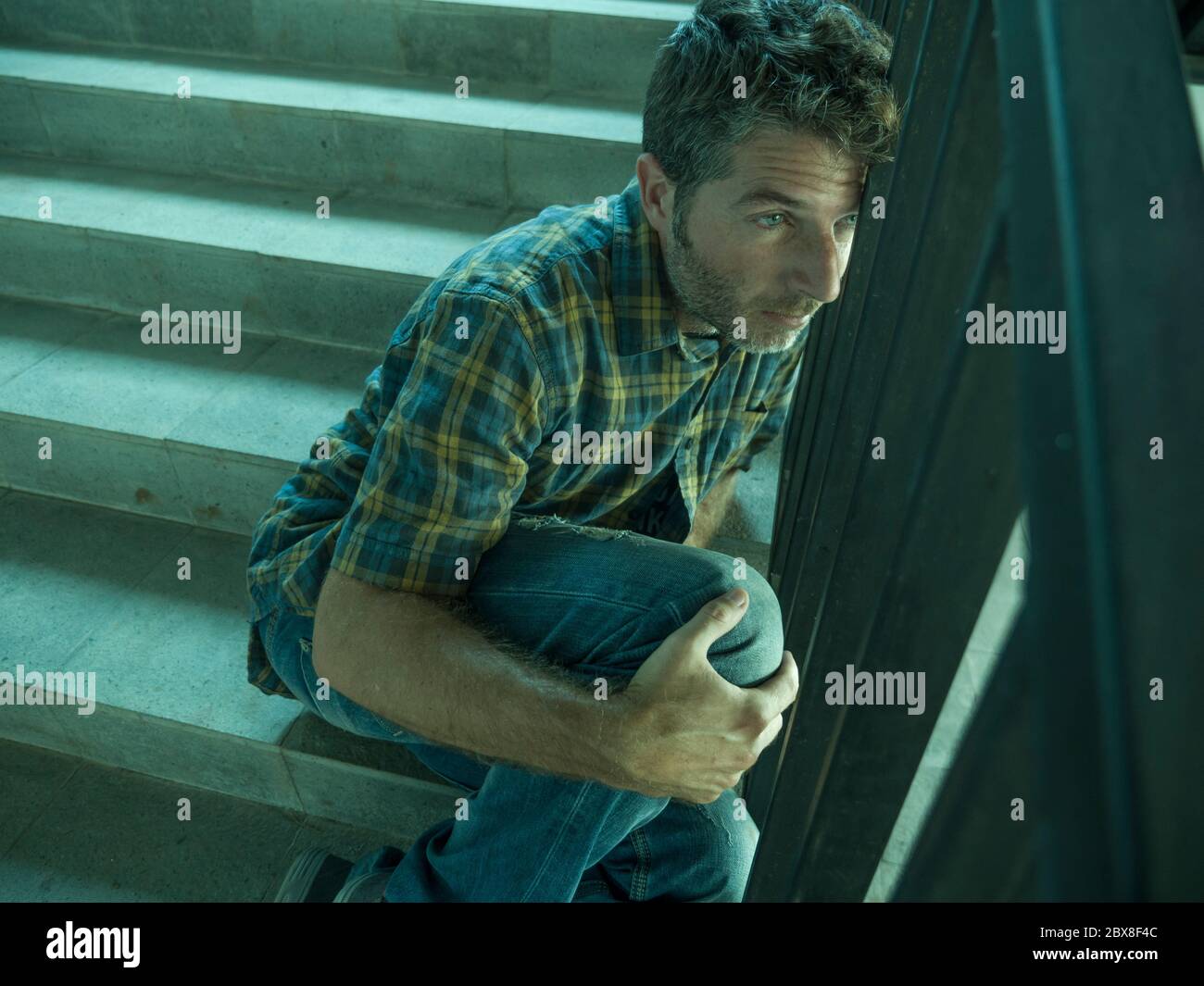 dramatic lifestyle portrait of young depressed and sad man sitting ...