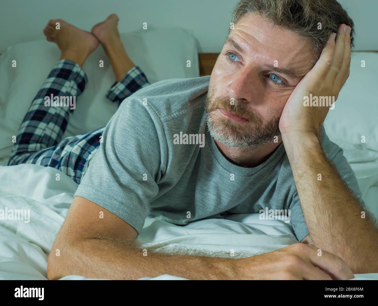 dramatic lifestyle portrait of young sad and depressed man lying ...