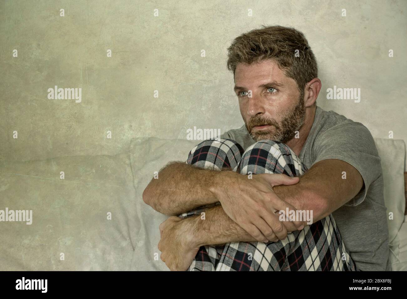 dramatic lifestyle portrait of young sad and depressed man lying ...