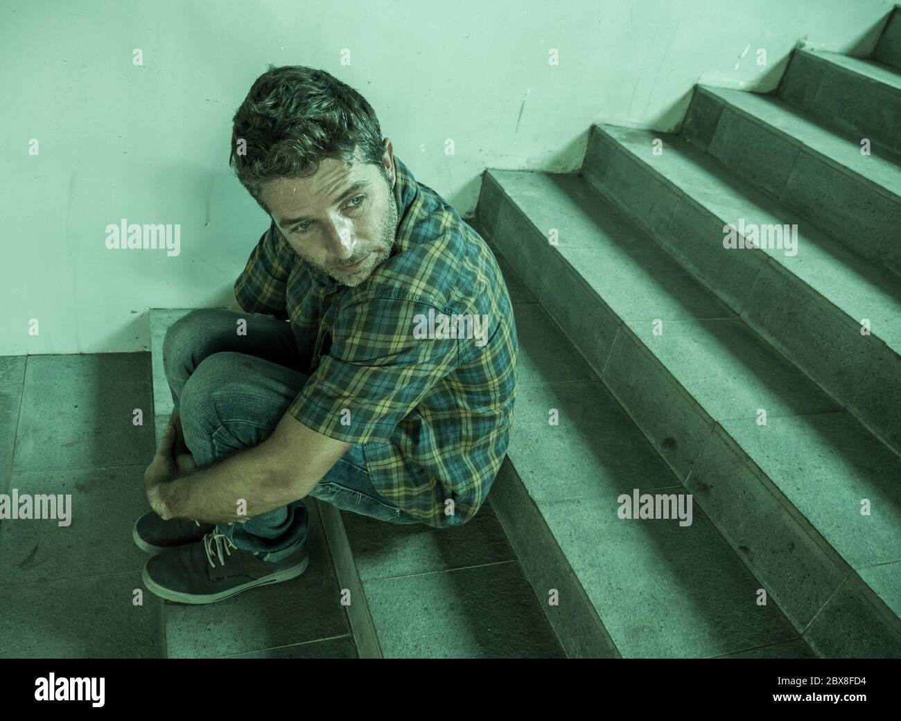 dramatic lifestyle portrait of young depressed and sad man sitting ...