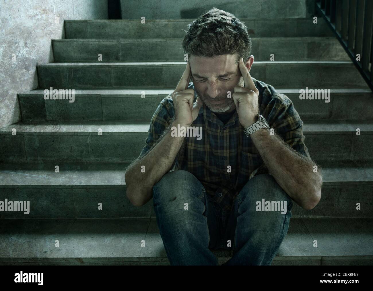 dramatic portrait of young depressed and paranoid man sitting outdoors ...