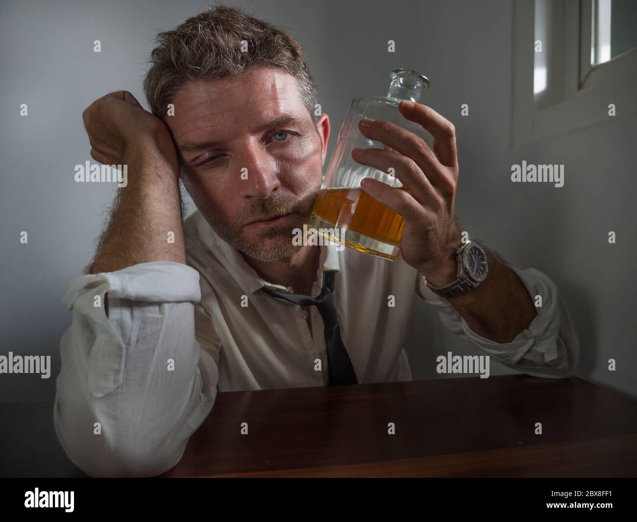 dramatic portrait of 30s to 40s drunk man in lose necktie drinking ...