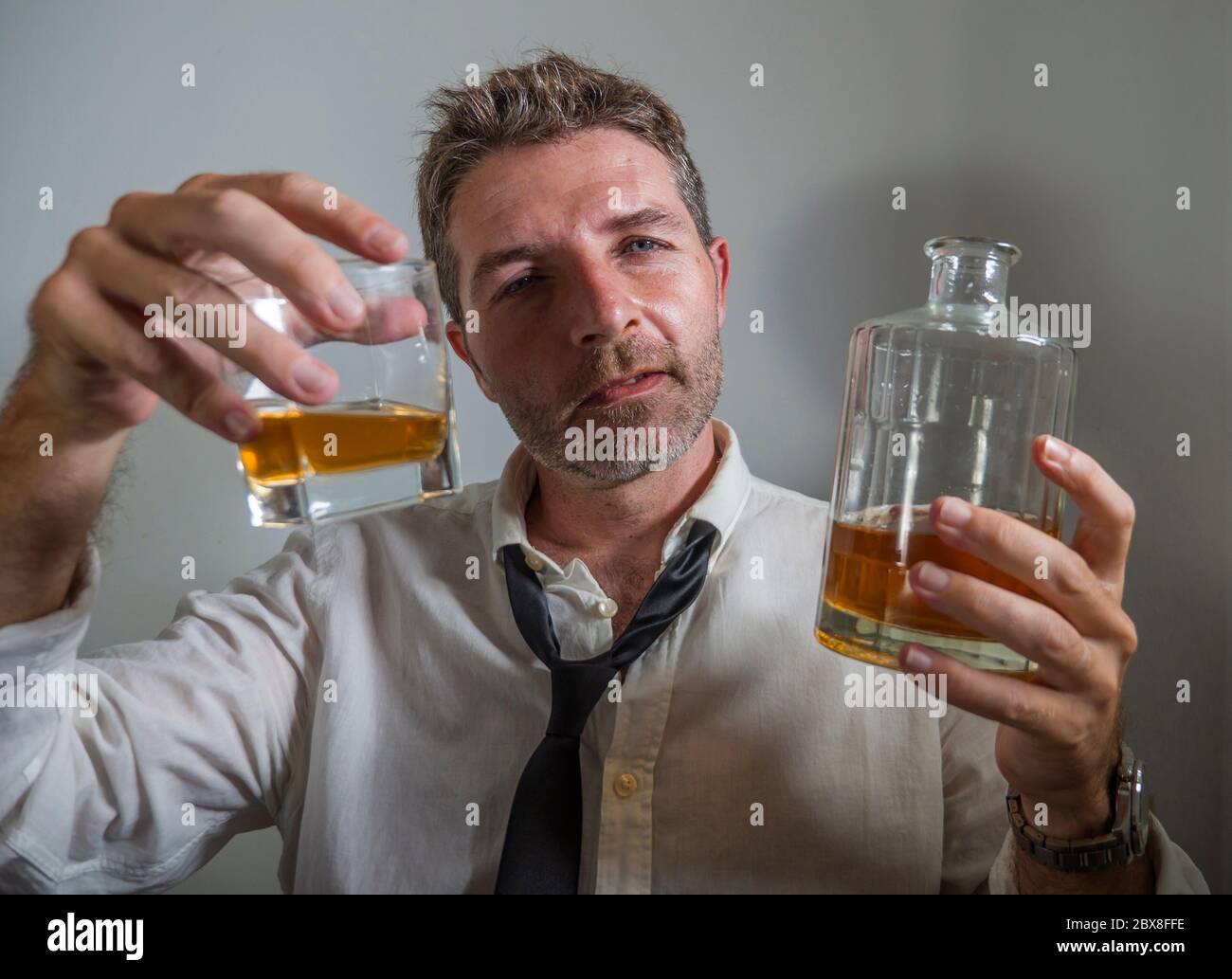dramatic portrait of 30s to 40s man in lose necktie drinking alcohol ...
