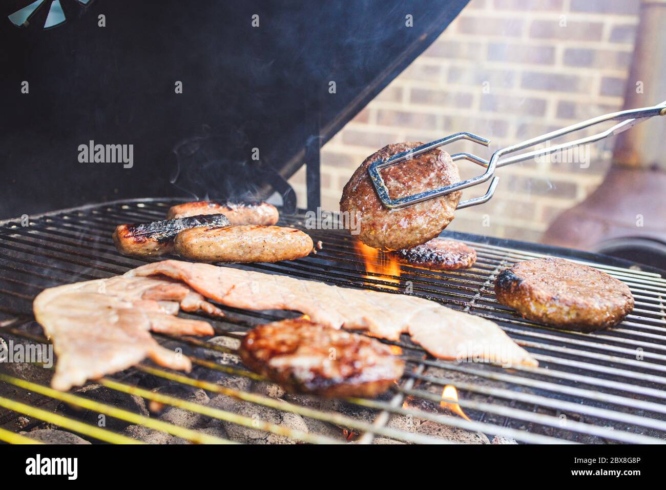 Summer time outdoor BBQ cooking meat with flames Stock Photo - Alamy