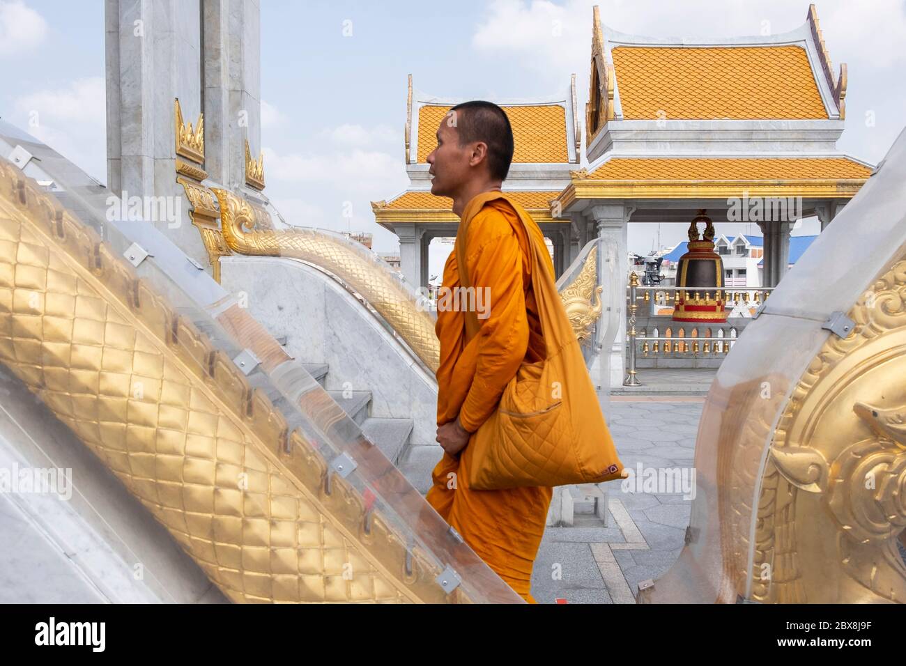 Buddhist monk walking up the stairs of the Wat Traimit, the Temple of ...