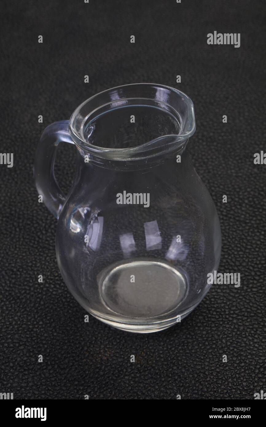 Empty glass jug over black background Stock Photo - Alamy