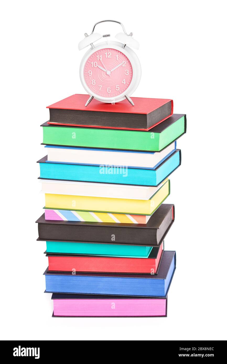 An alarm clock on top of stack of colorful books with different sprayed ...