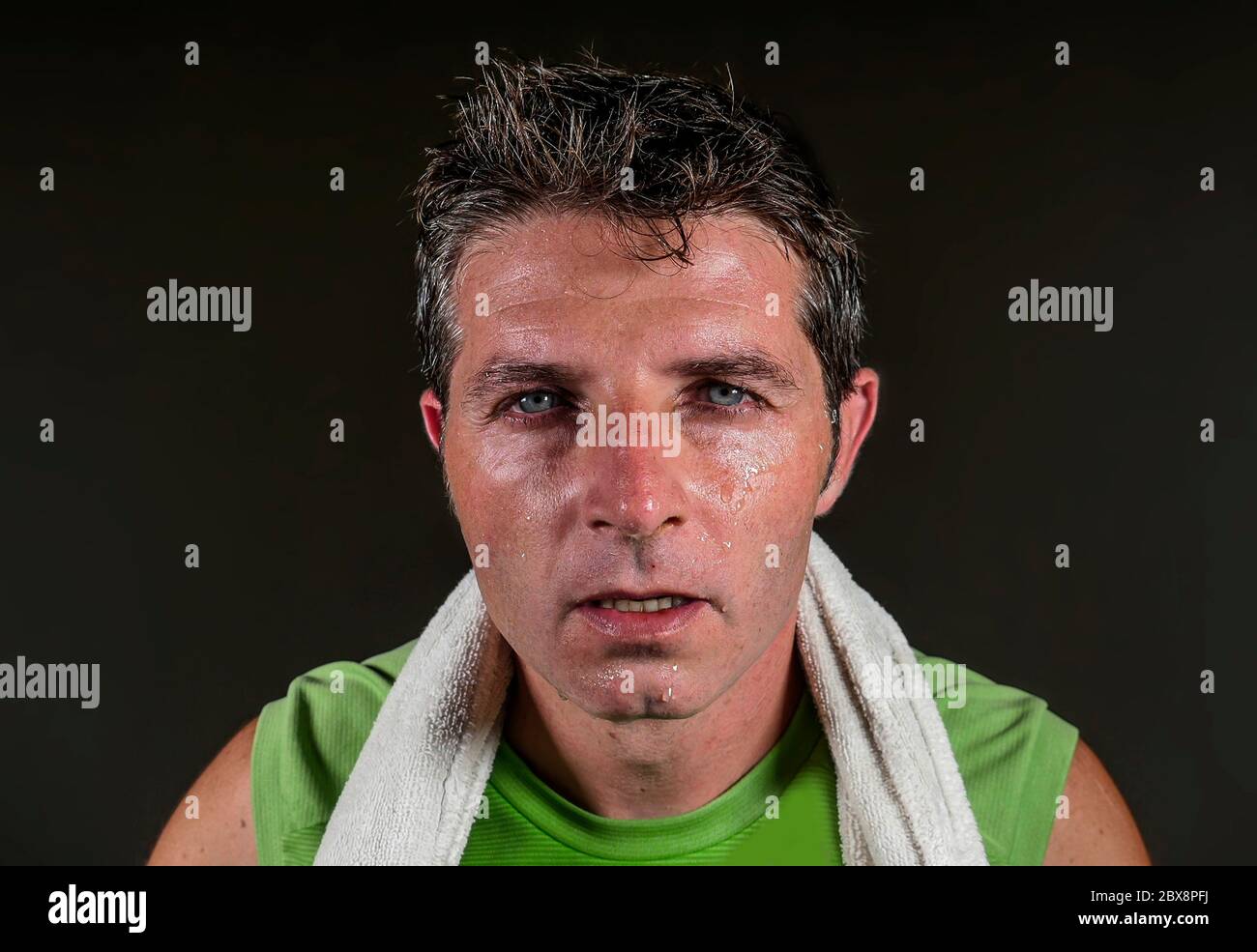 young tired and exhausted sport man with towel on his neck sweaty and ...