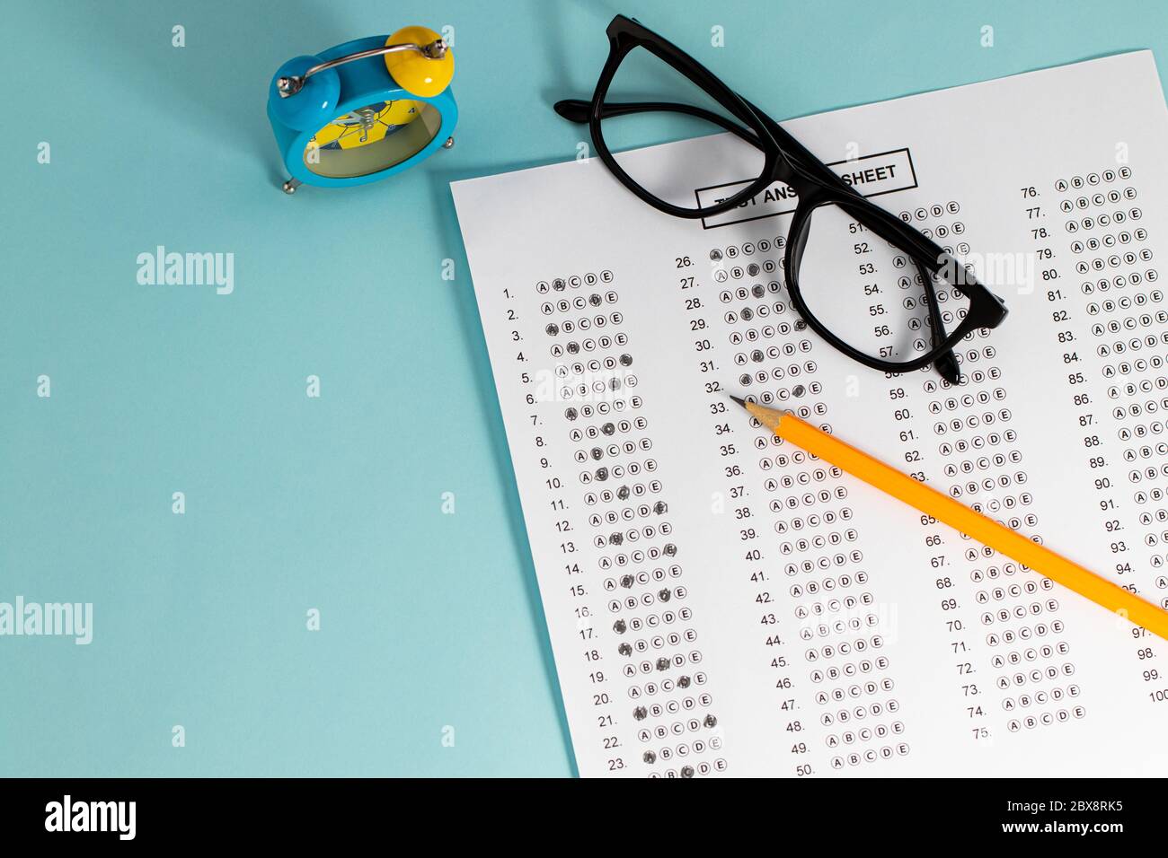 Take the exam, write the exam. Exam paper with alarm clock on blue ...