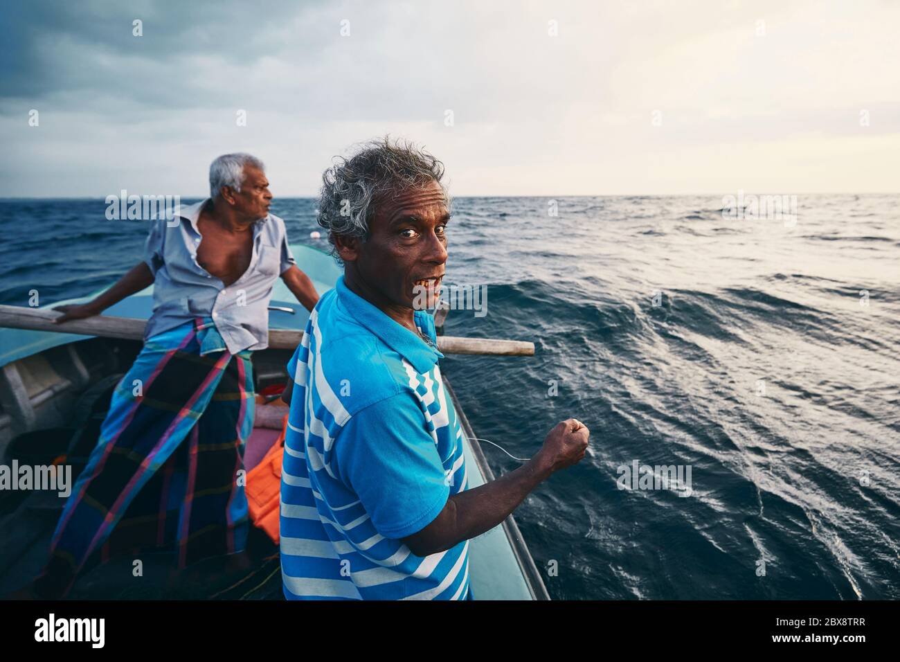 Hard work on sea. Two fishermen on fishing boat near coastline of Sri ...