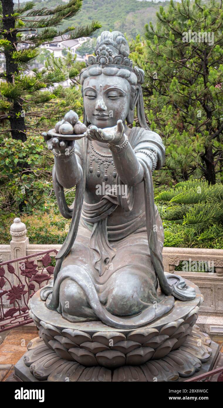 Buddhist Deva statue offering fruit to the Tian Tan Big Buddha statue ...
