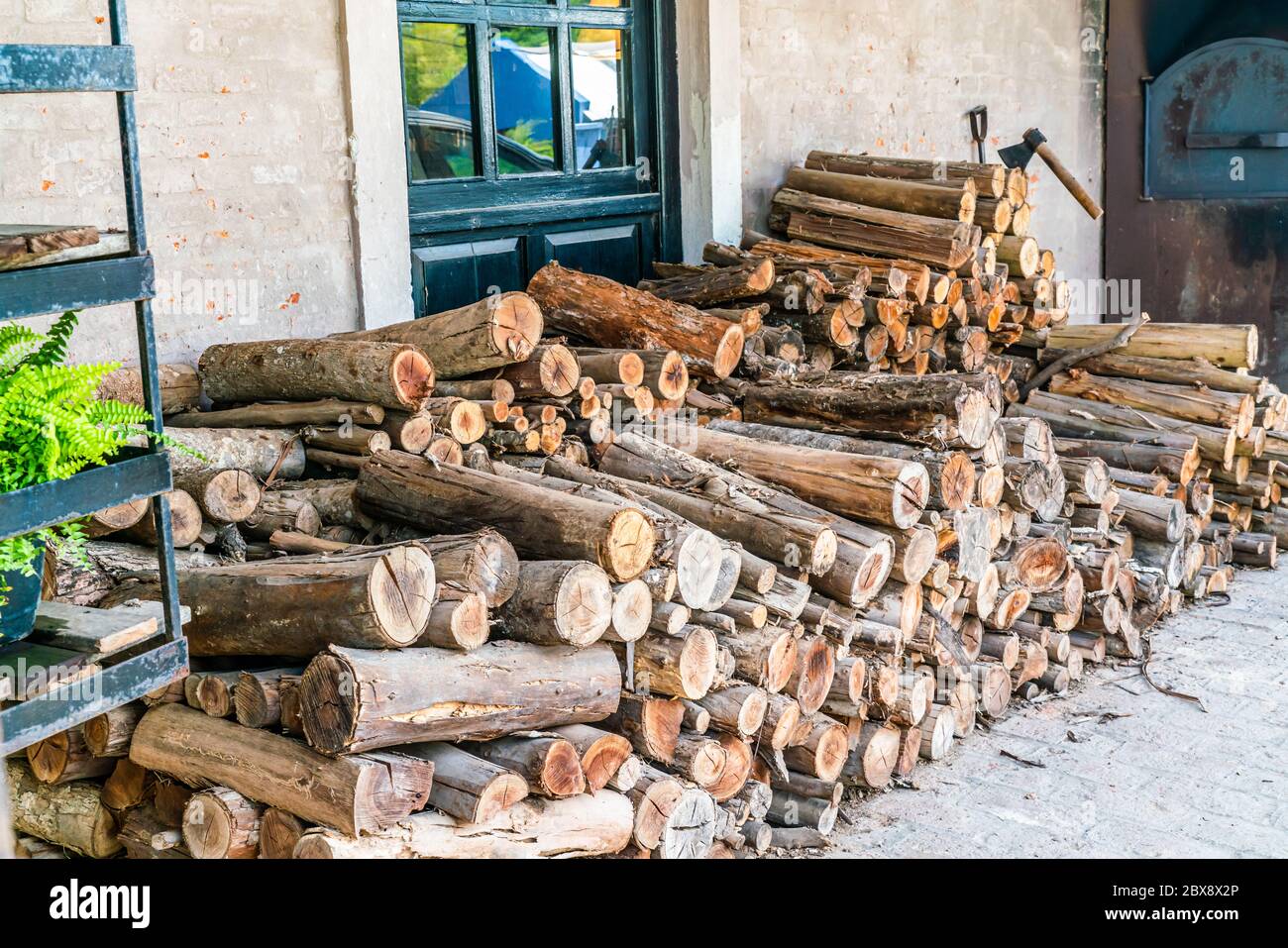 piled wood in front of a wall with a classic door in Uruguay Stock ...