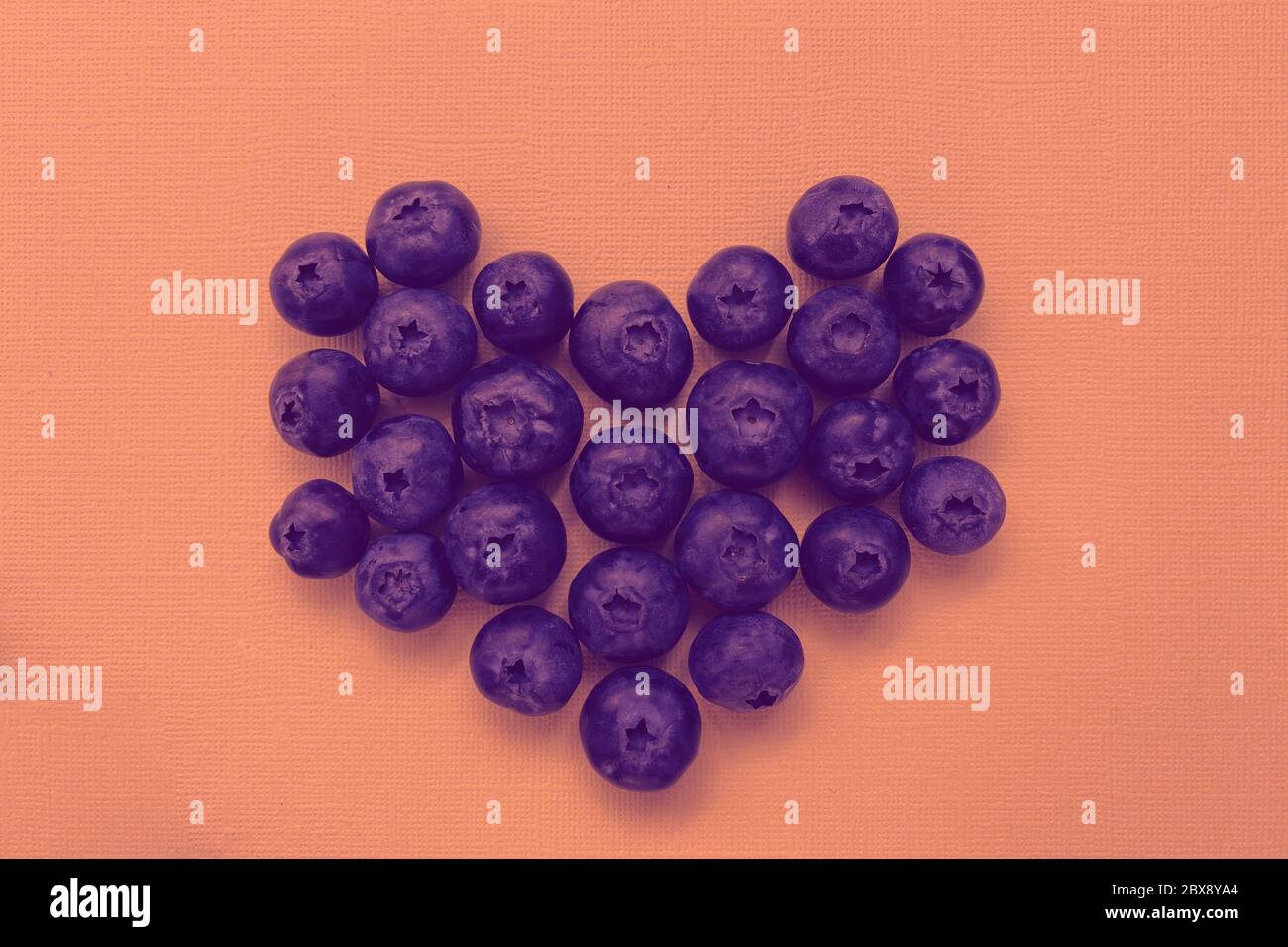 Blueberries in the shape of heart on a yellow background. The concept ...