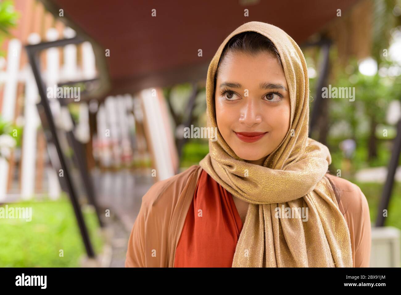 Face of young beautiful Indian Muslim woman thinking in the city with ...