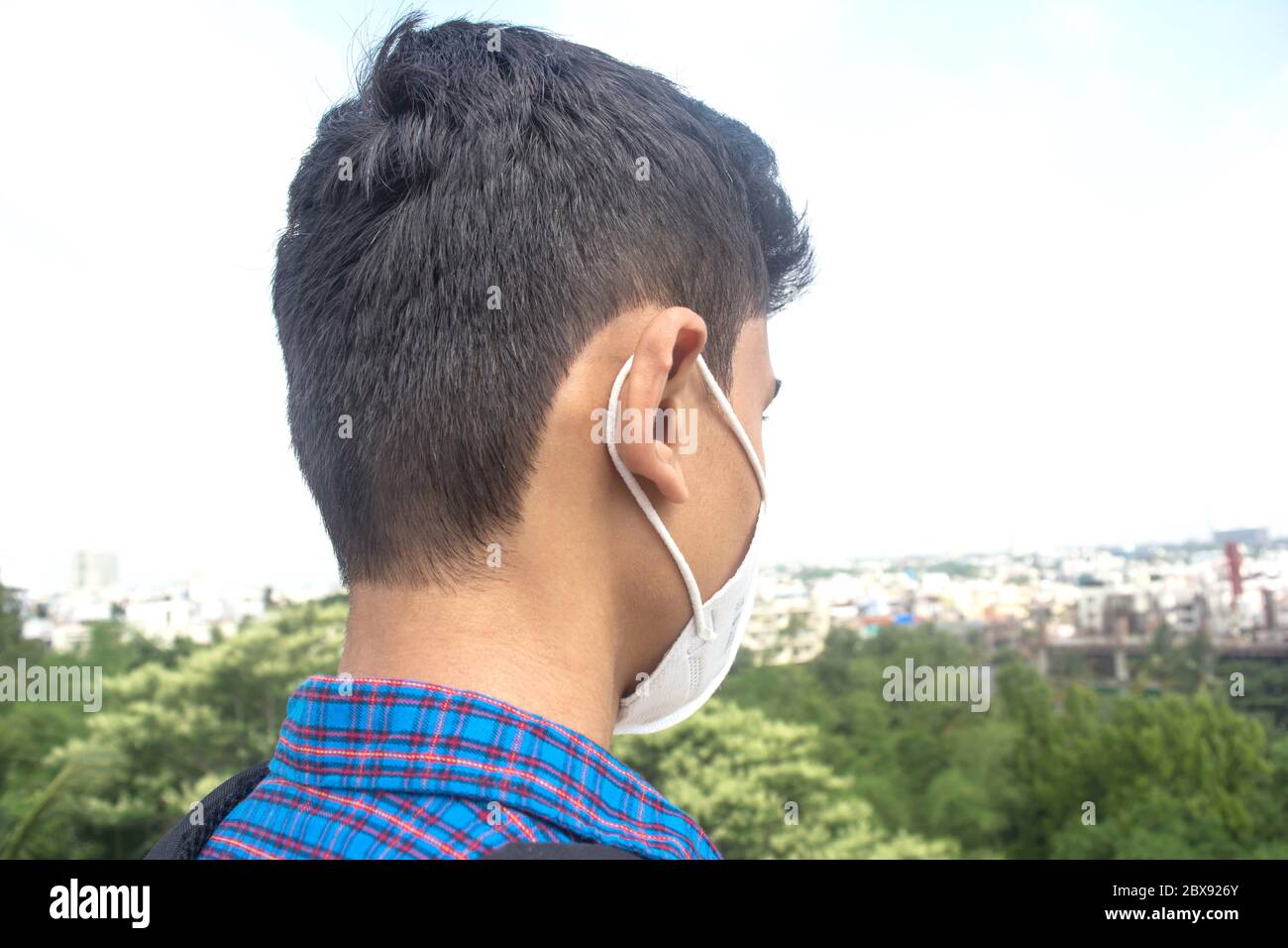 Back view of young man wearing face mask. city background Stock Photo ...