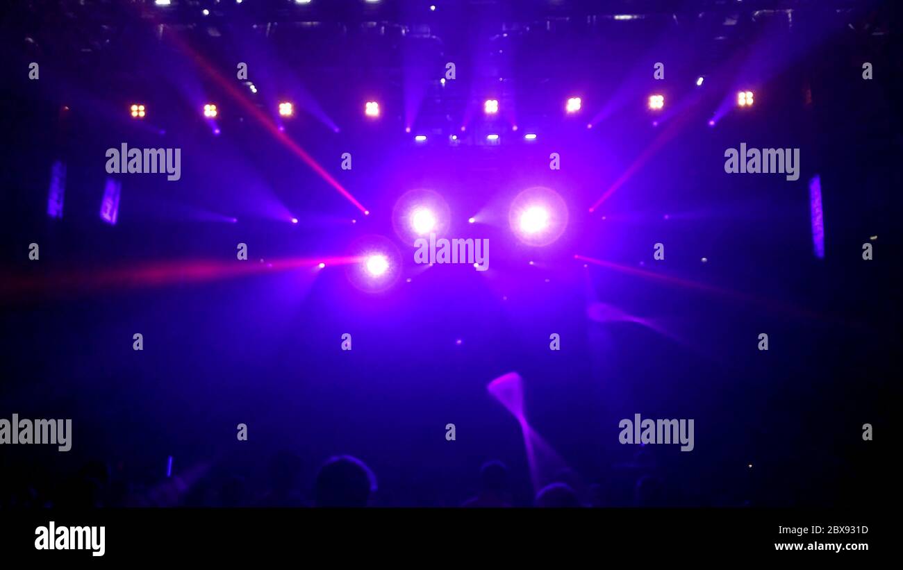 Audience with hands raised at a concert and lights streaming from the ...