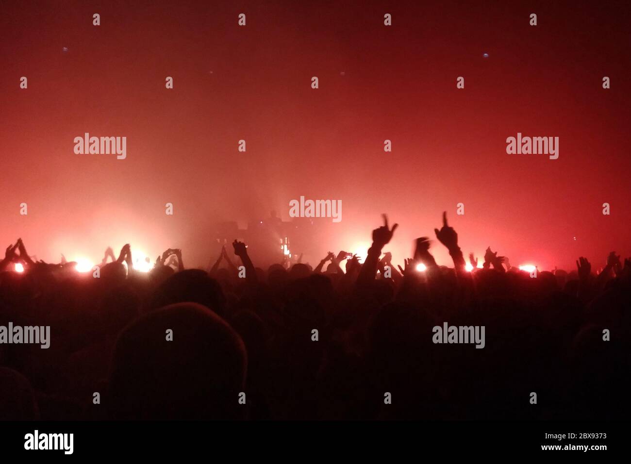 Audience with hands raised at a concert and lights streaming from the ...