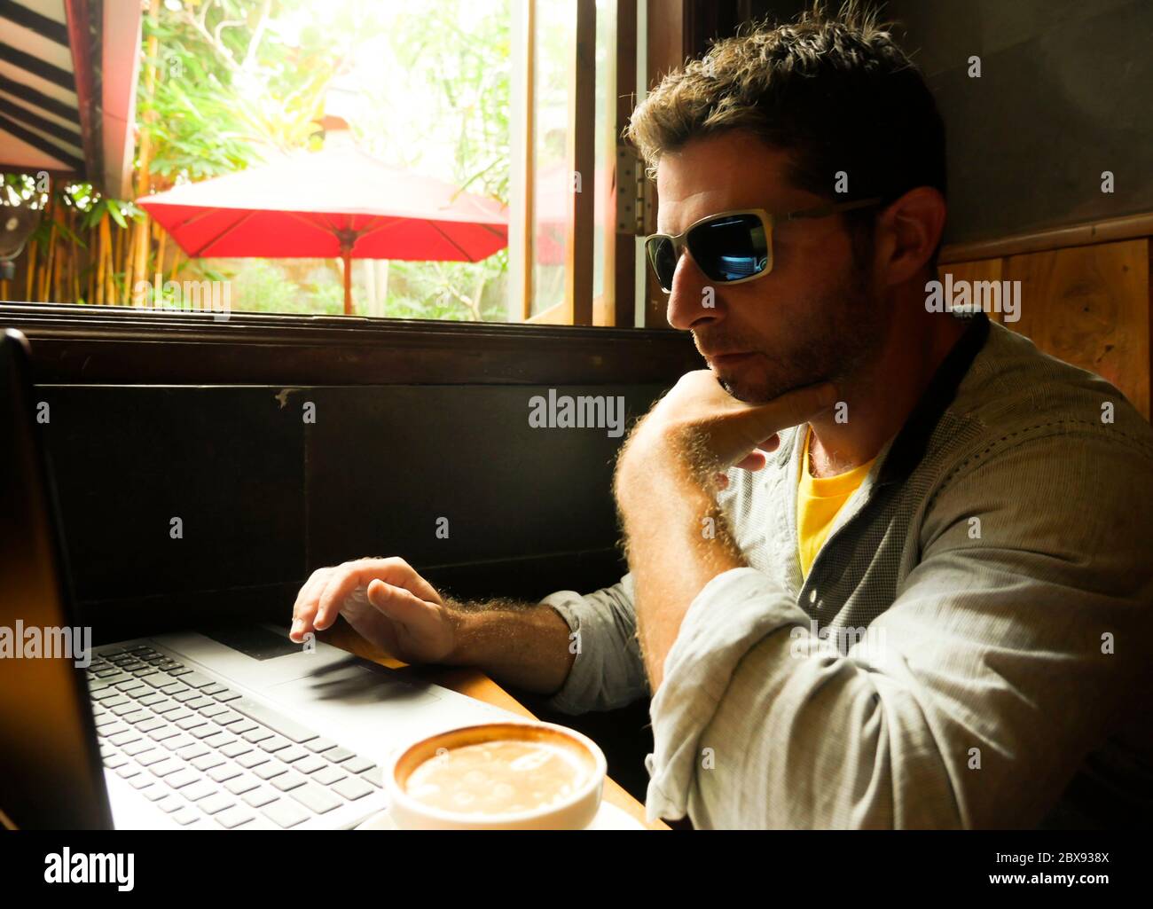 attractive thoughtful and pensive millennial man working from internet ...
