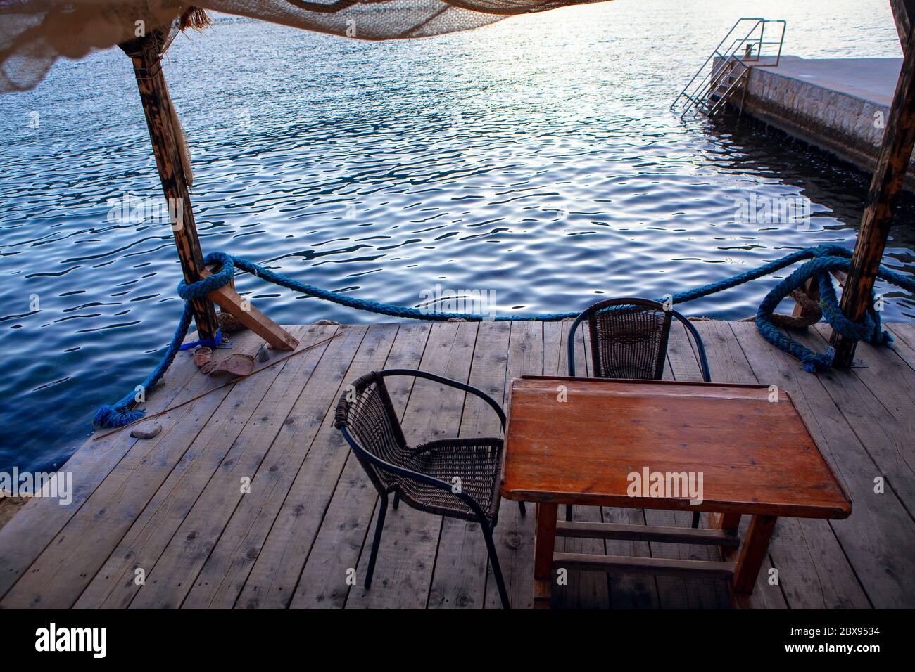 seaside terrace ,wooden pier with a table and chairs Stock Photo - Alamy