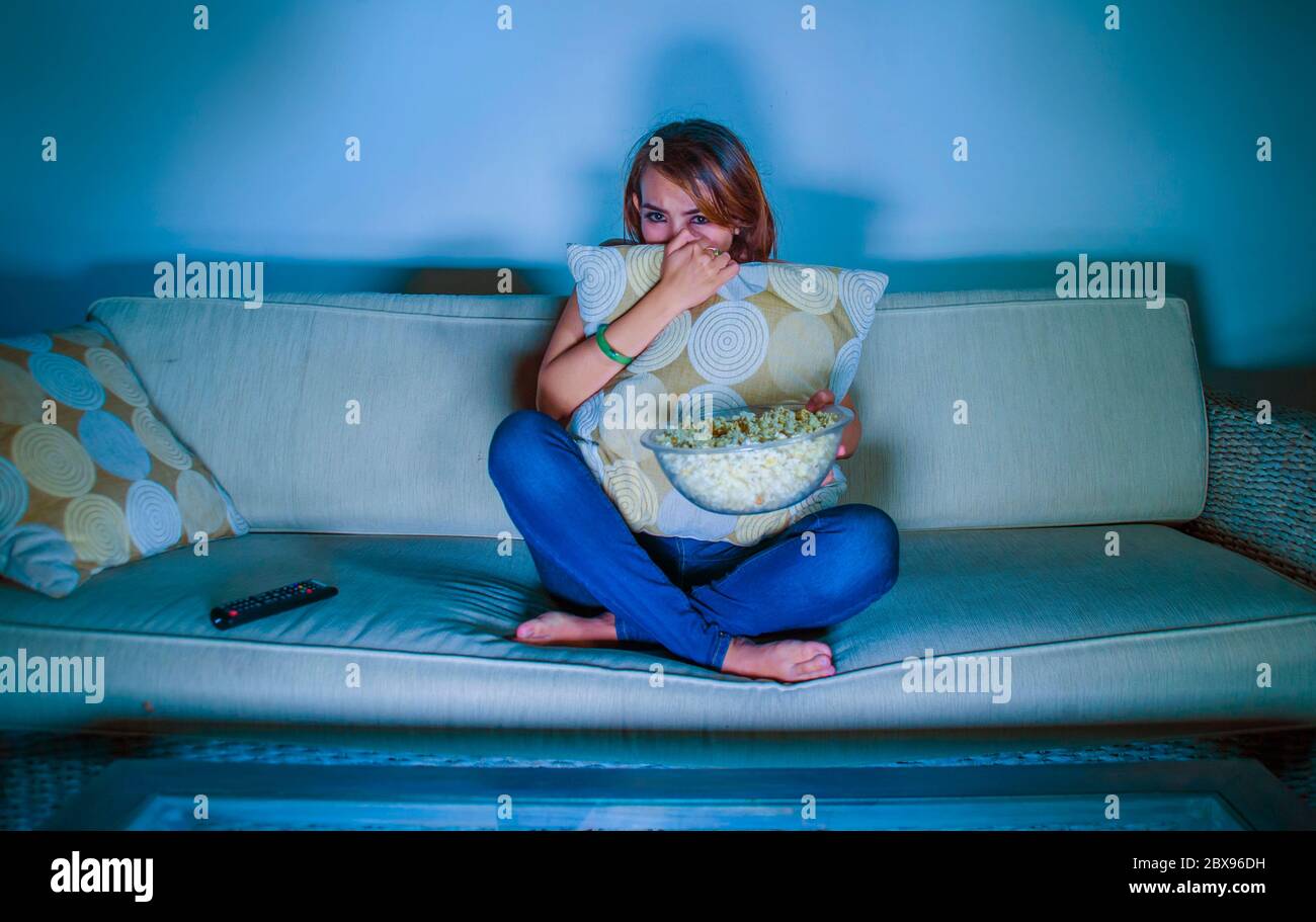 young beautiful and scared woman watching horror or suspense movie ...