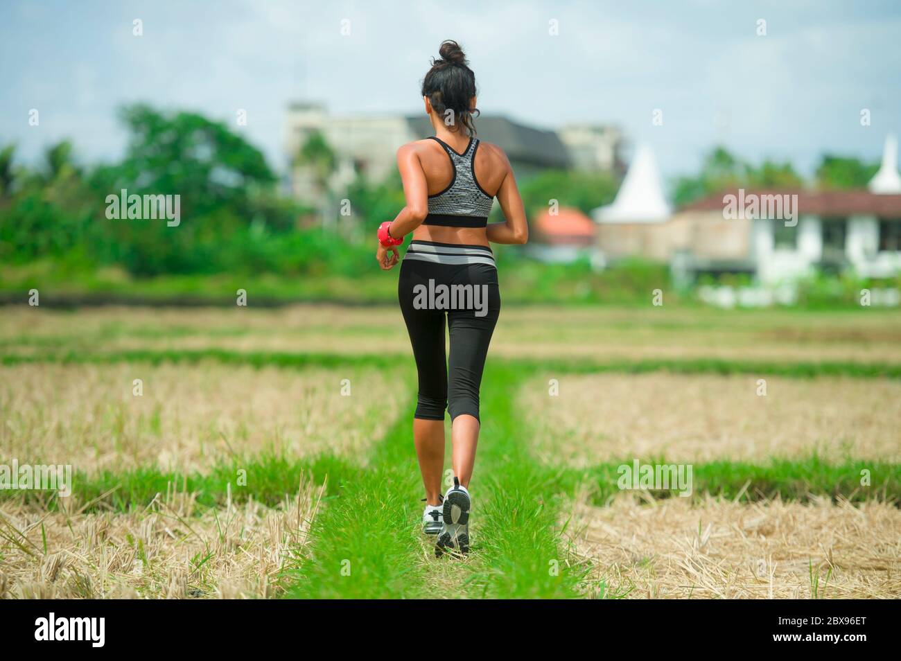 back view of young runner woman with attractive and fit body in running ...