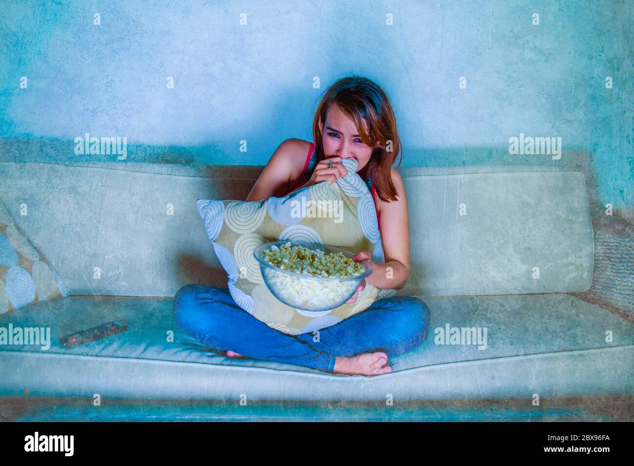 young beautiful and scared woman watching horror suspense movie and ...