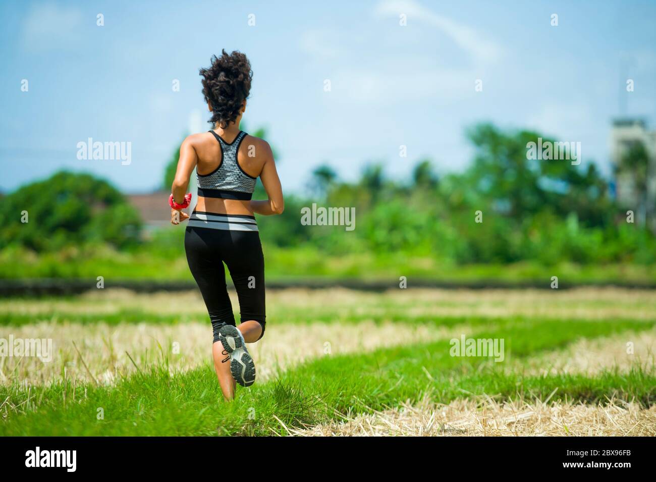 back view of young runner woman with attractive and fit body in running ...