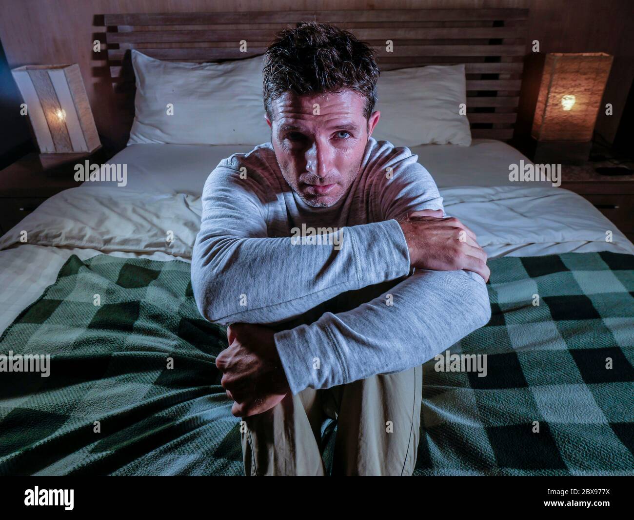 indoors portrait of young desperate and depressed man at home bedroom ...