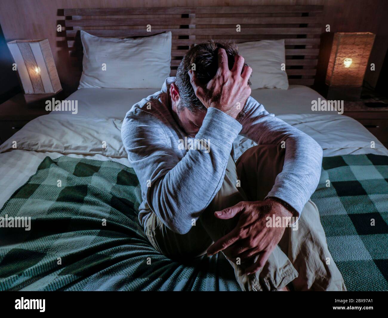 indoors portrait of young desperate and depressed man at home bedroom ...