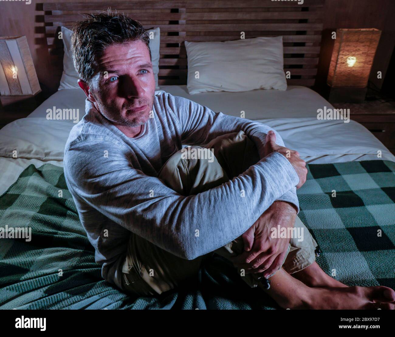 indoors portrait of young desperate and depressed man at home bedroom ...